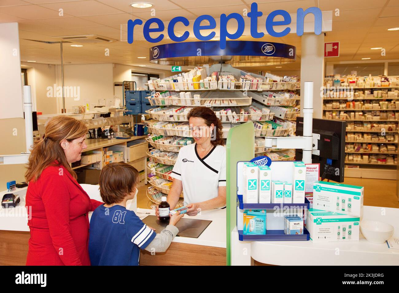 Netherlands, Velp, in a drugstore, a mother and son are collecting the ...
