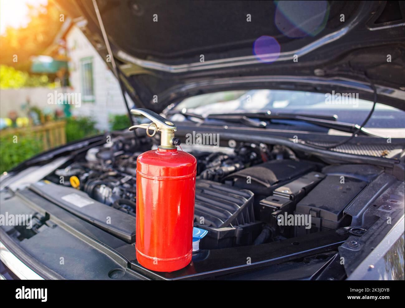 A car powder fire extinguisher is in a car with an open hood. The ...