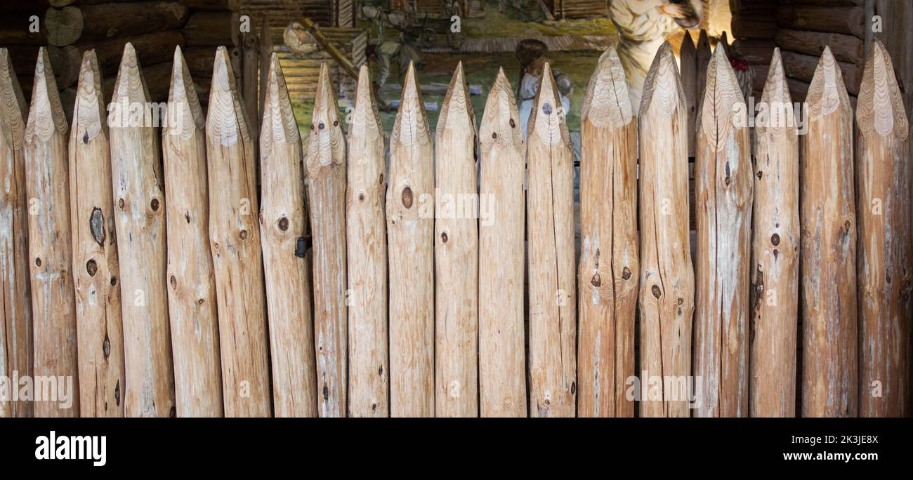 Old wooden fence made of pointed logs. Palisade, copy space for text ...