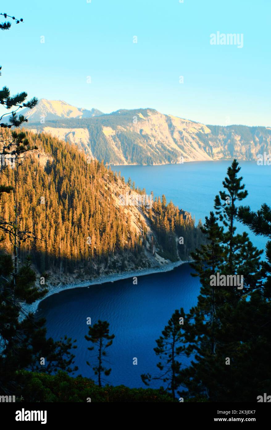 An aerial view of clear blue lake surrounded by mountain forests and ...