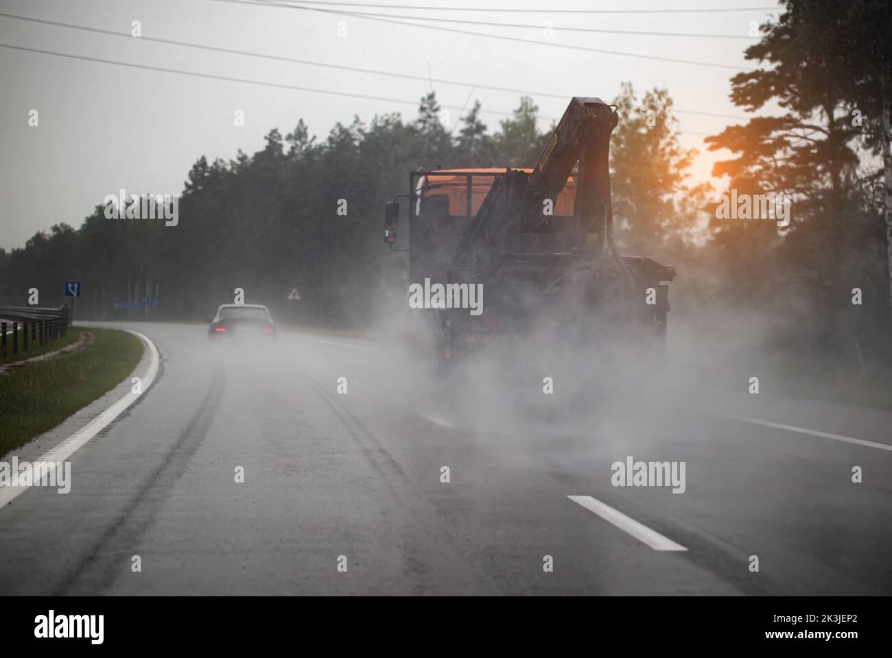 A passenger car overtakes a truck on a slippery rainy highway. Poor ...