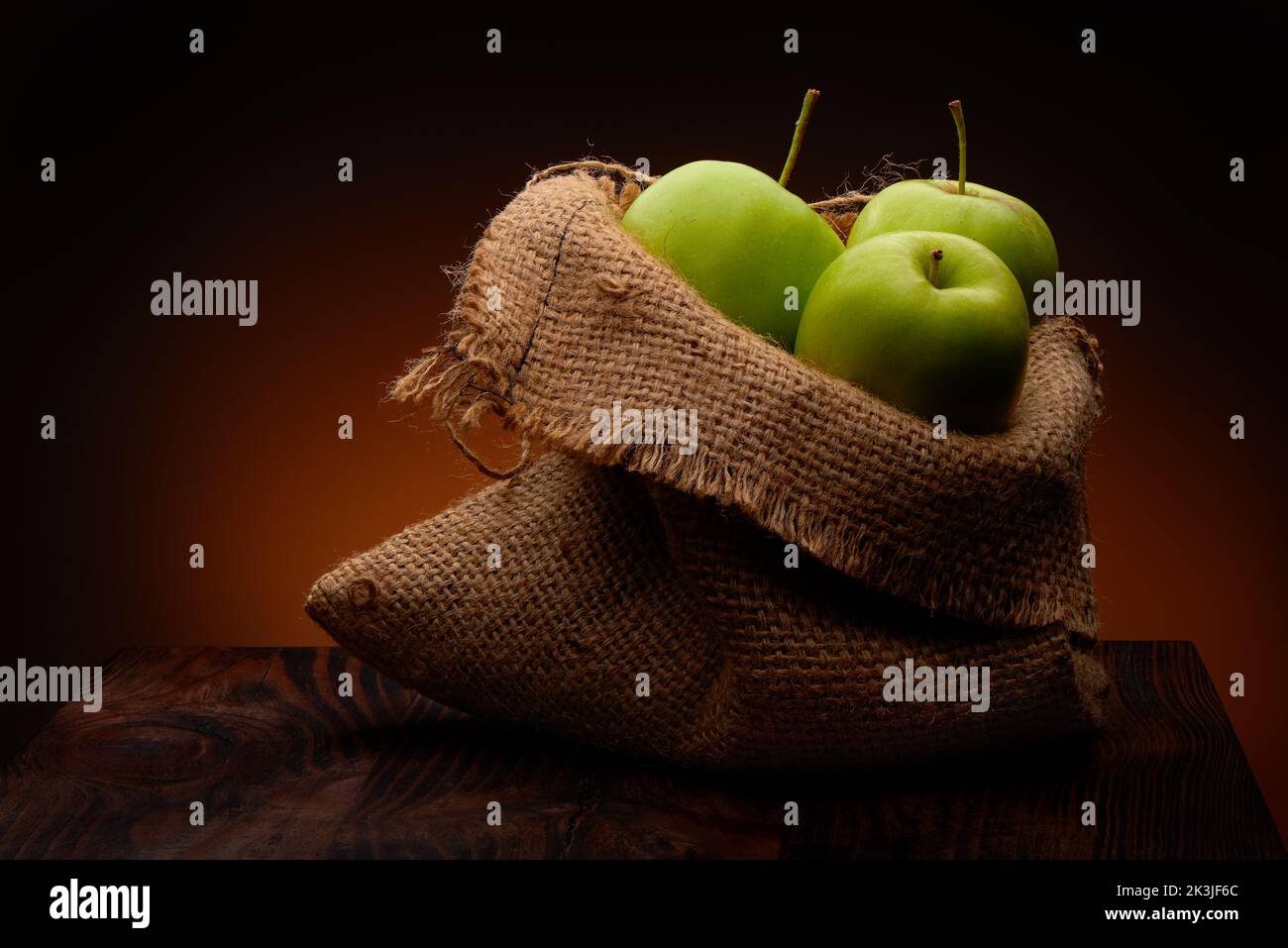 Organic green apples in burlap bag on dark wooden table and warm rustic ...