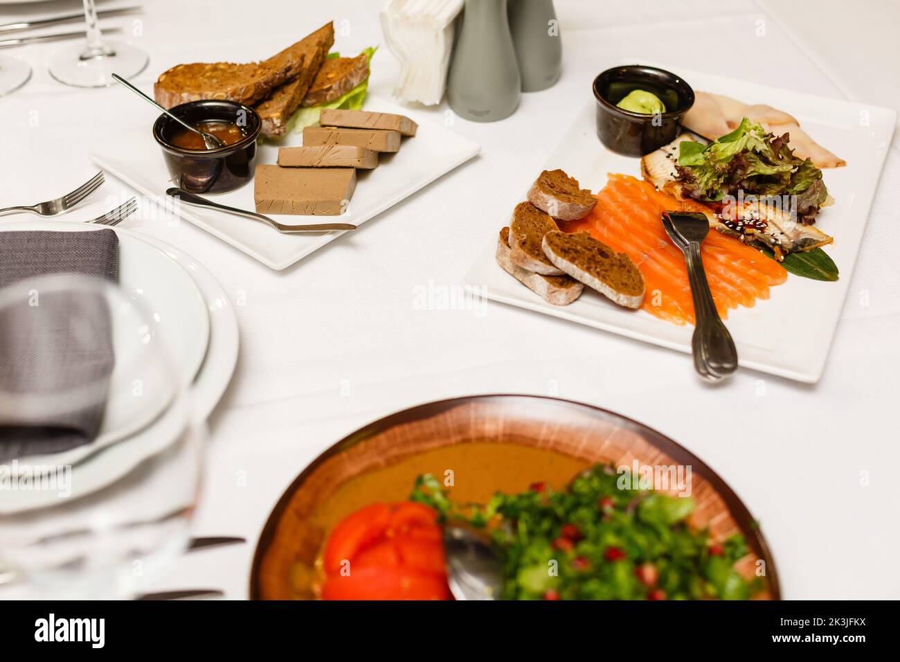 Fish platter, meat platter, sauce, and bread in restaurant. Sliced fish ...