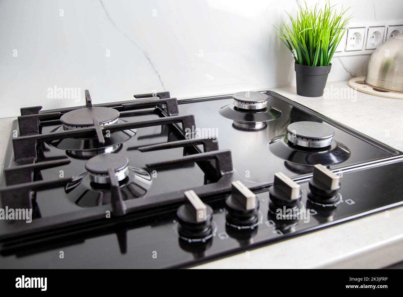 Modern gas hob with cast iron grate against white porcelain tiles on ...