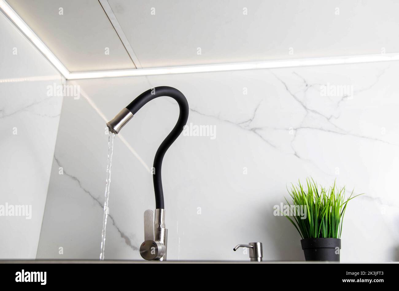 Contemporary kitchen faucet with curved spout set against white ...