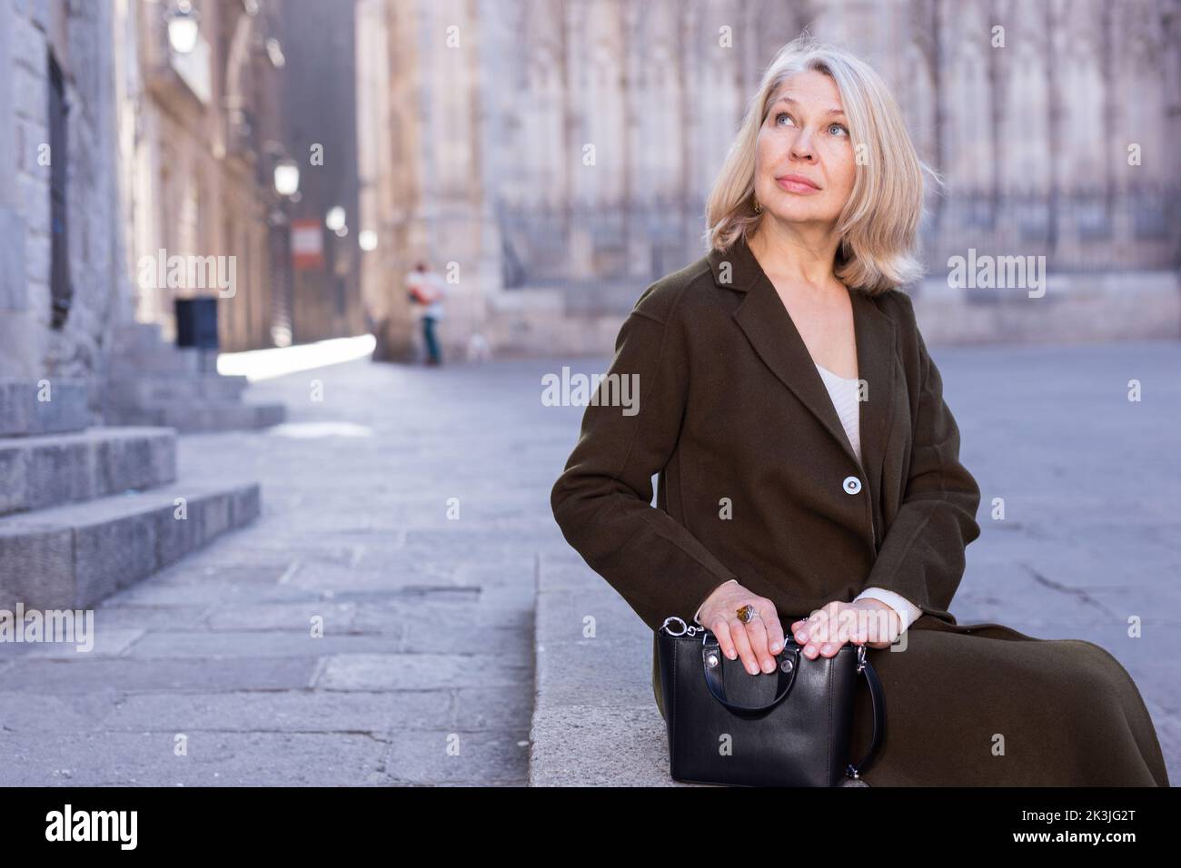 Portrait of stylish woman sitting on a stone bench Stock Photo - Alamy