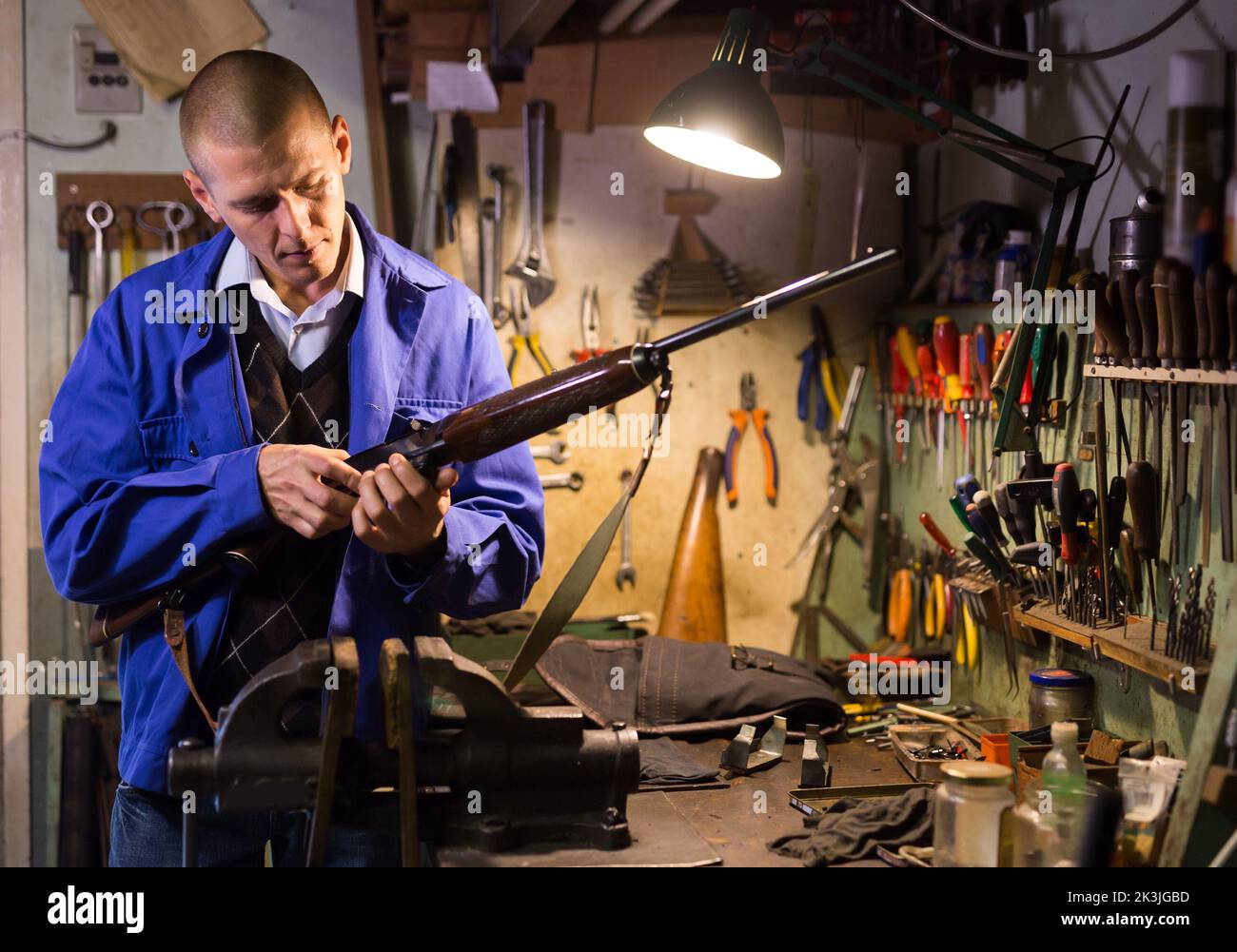 Gunsmith examines an automatic rifle before being repaired in weapons ...