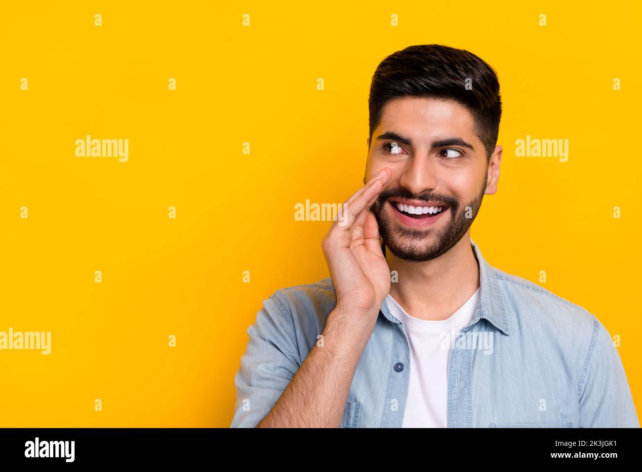 Photo of cute nice brunet guy say secret look empty space wear stylish ...