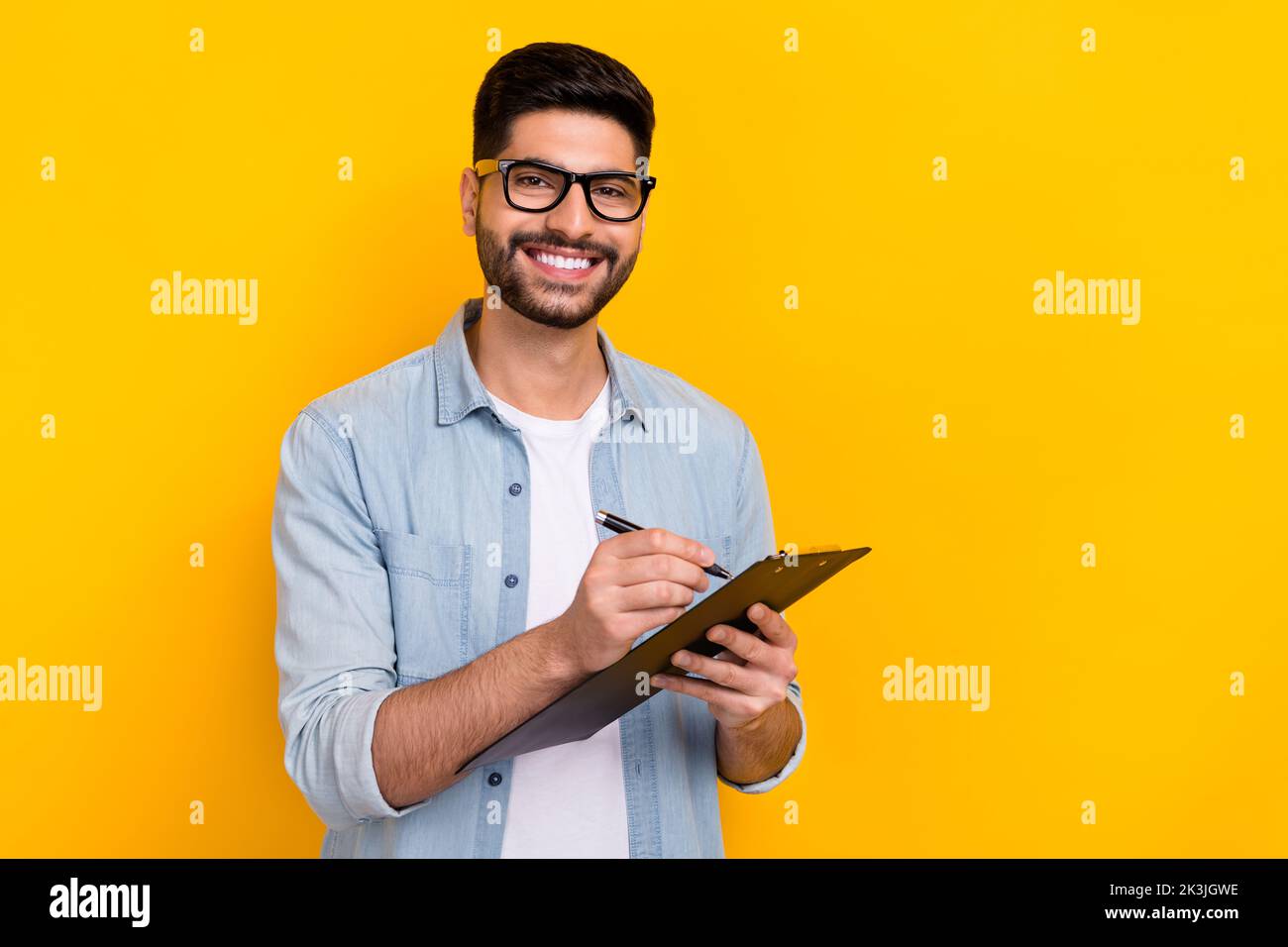 Portrait of young smiling happy man writing paper pad work document ...