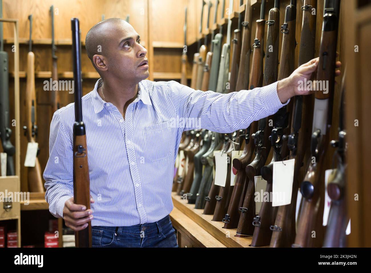 Portrait of confident man in gun shop showing rifle Stock Photo - Alamy