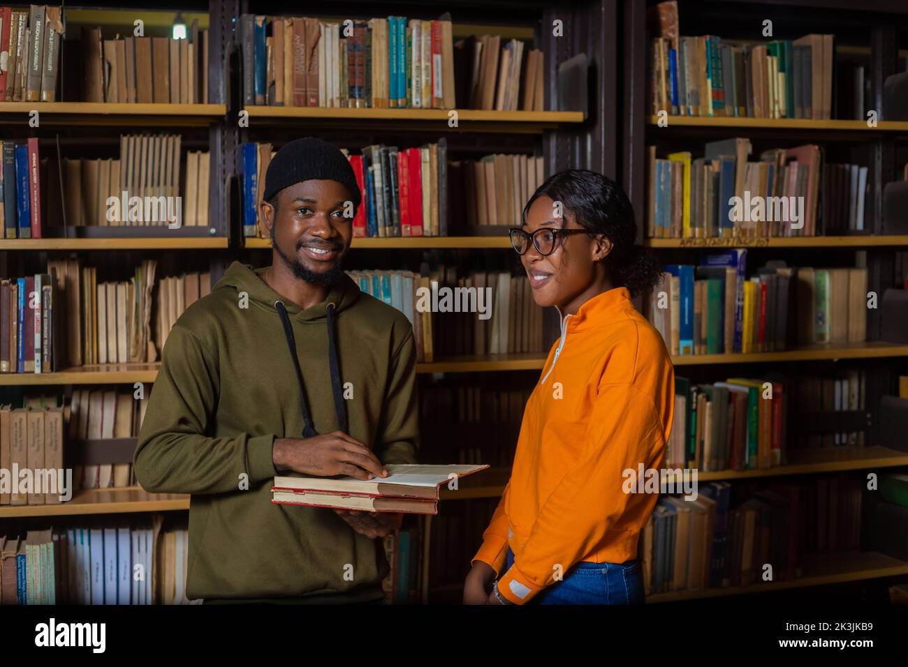 Two African American students discussing books at a library Stock Photo ...
