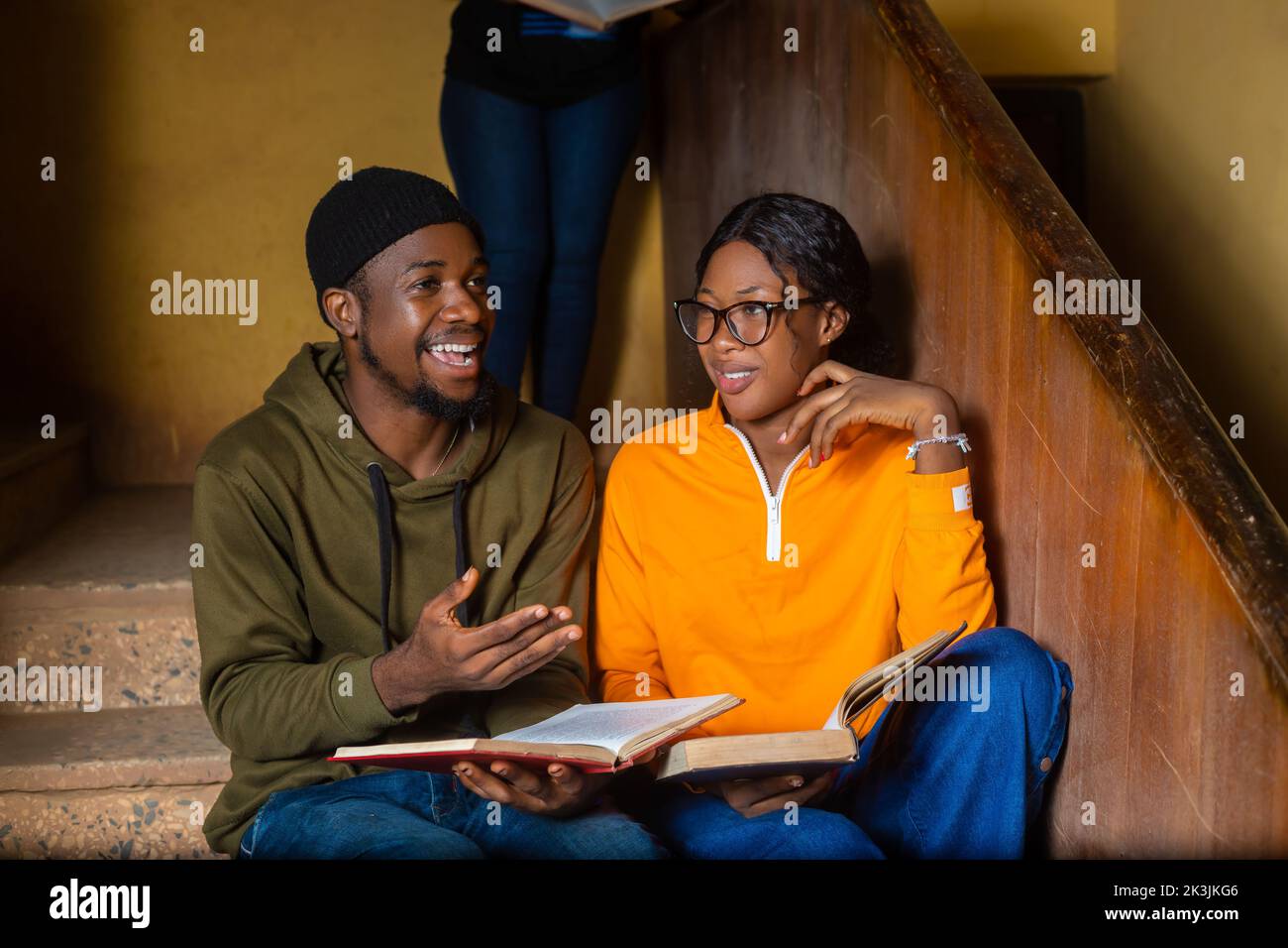 Two African American students reading books on the stairs at a library ...