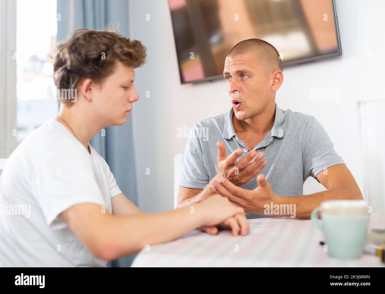 Portrait of teen boy having conversation with man in home Stock Photo ...