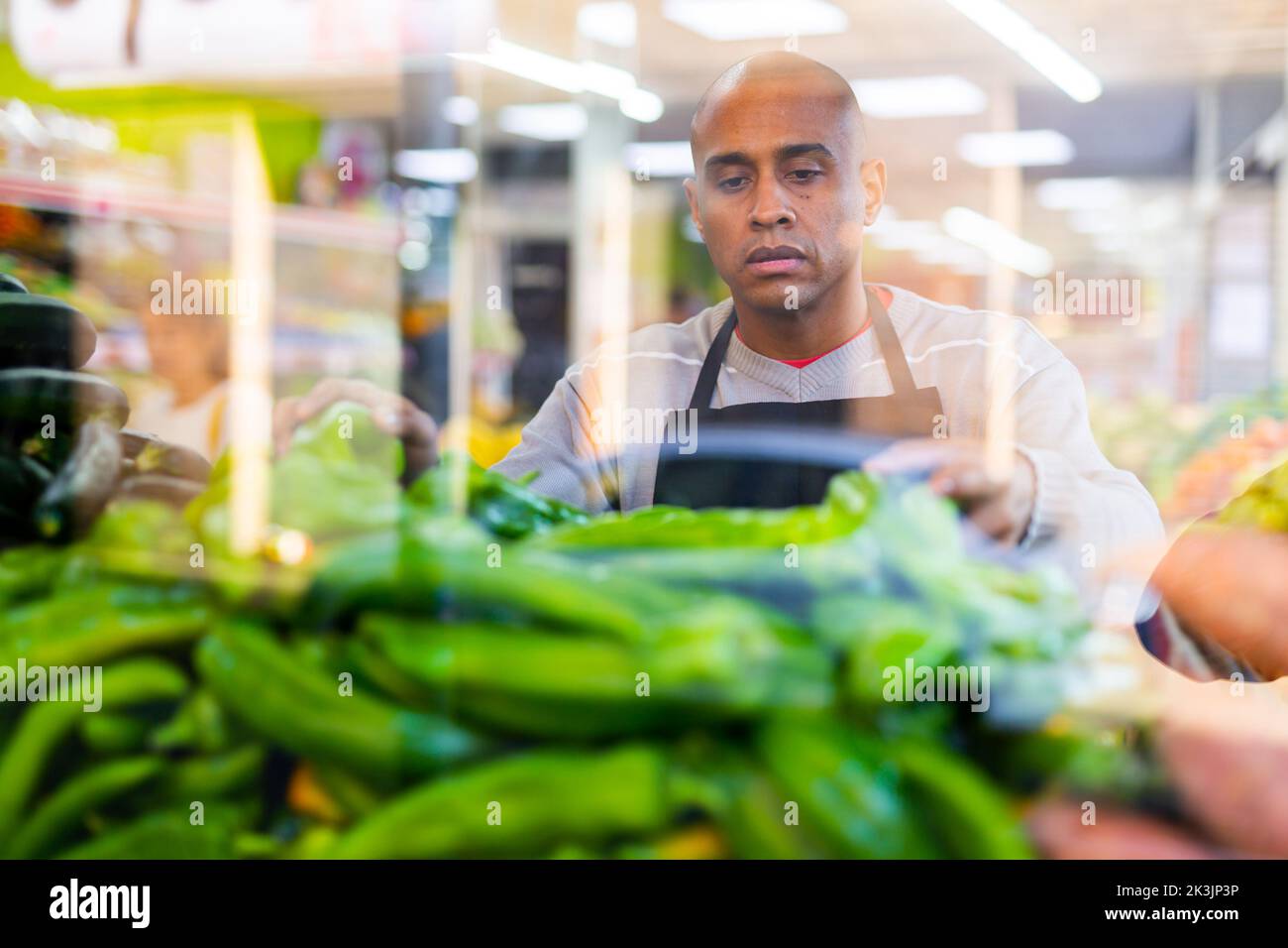 Supermarket worker in black apron cheking vegetables Stock Photo - Alamy