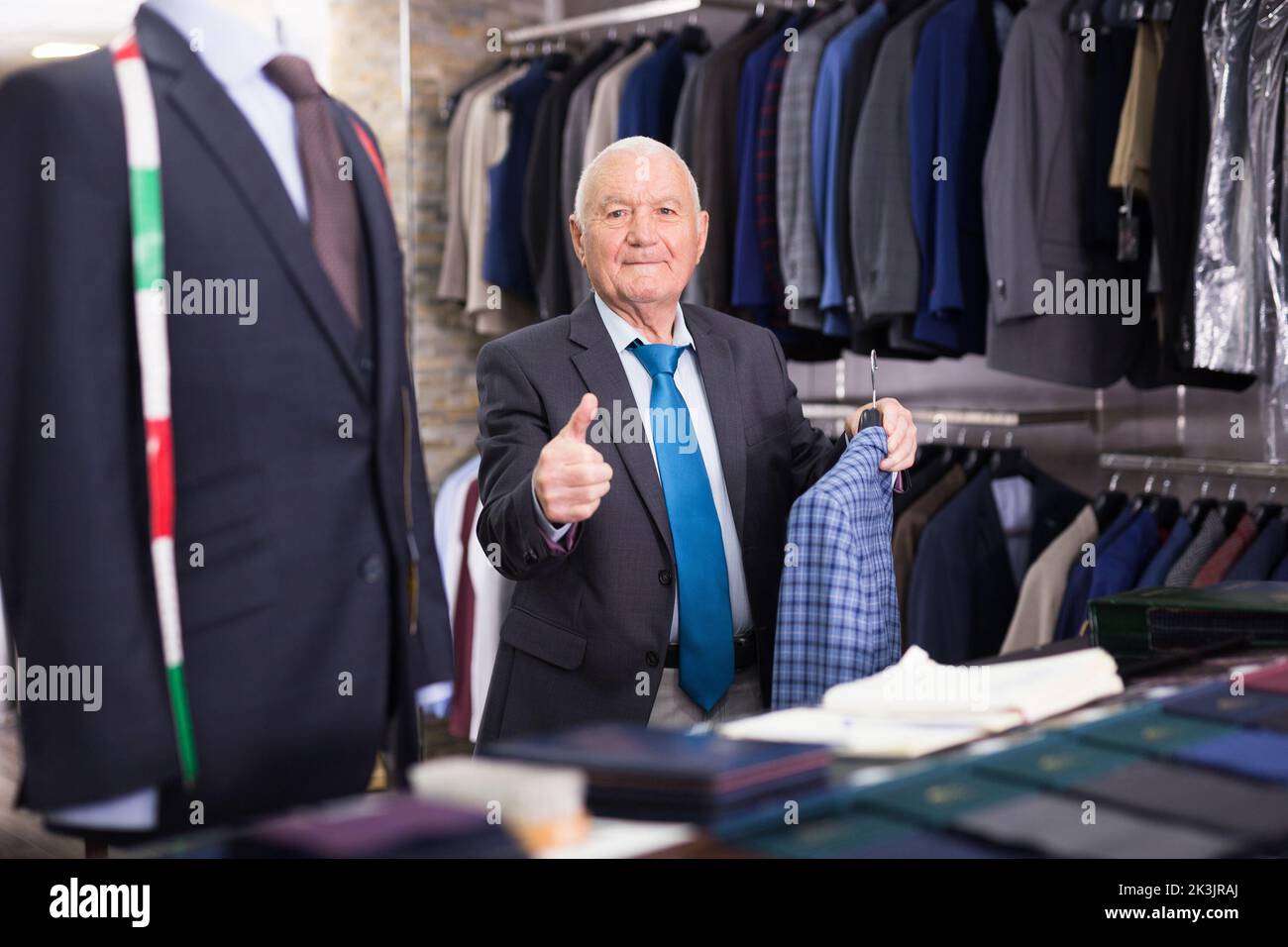 Happy senior citizen choosing fashionable jacket in clothing store and ...