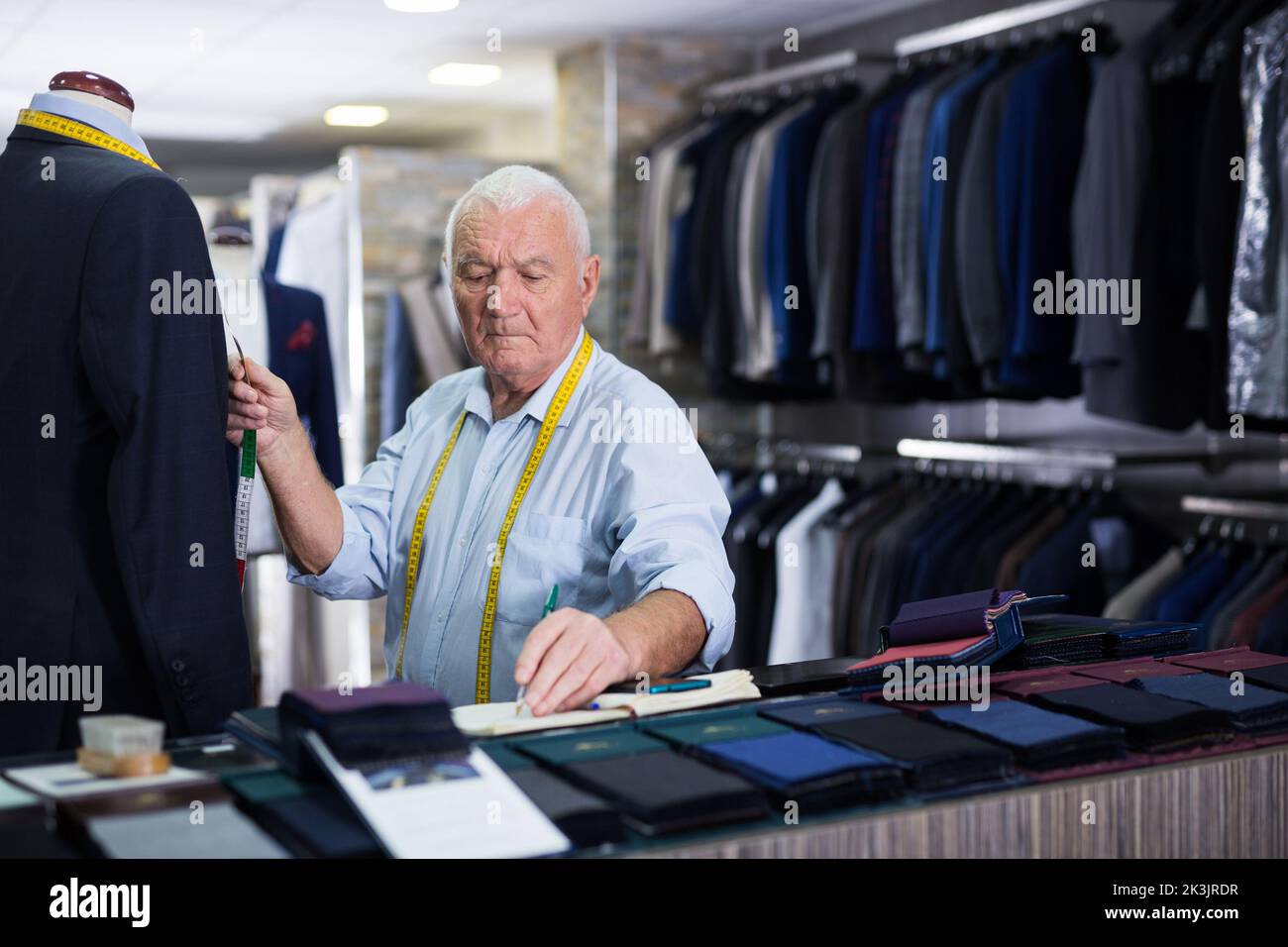 Mature tailor makes measurements of business suit at studio Stock Photo ...