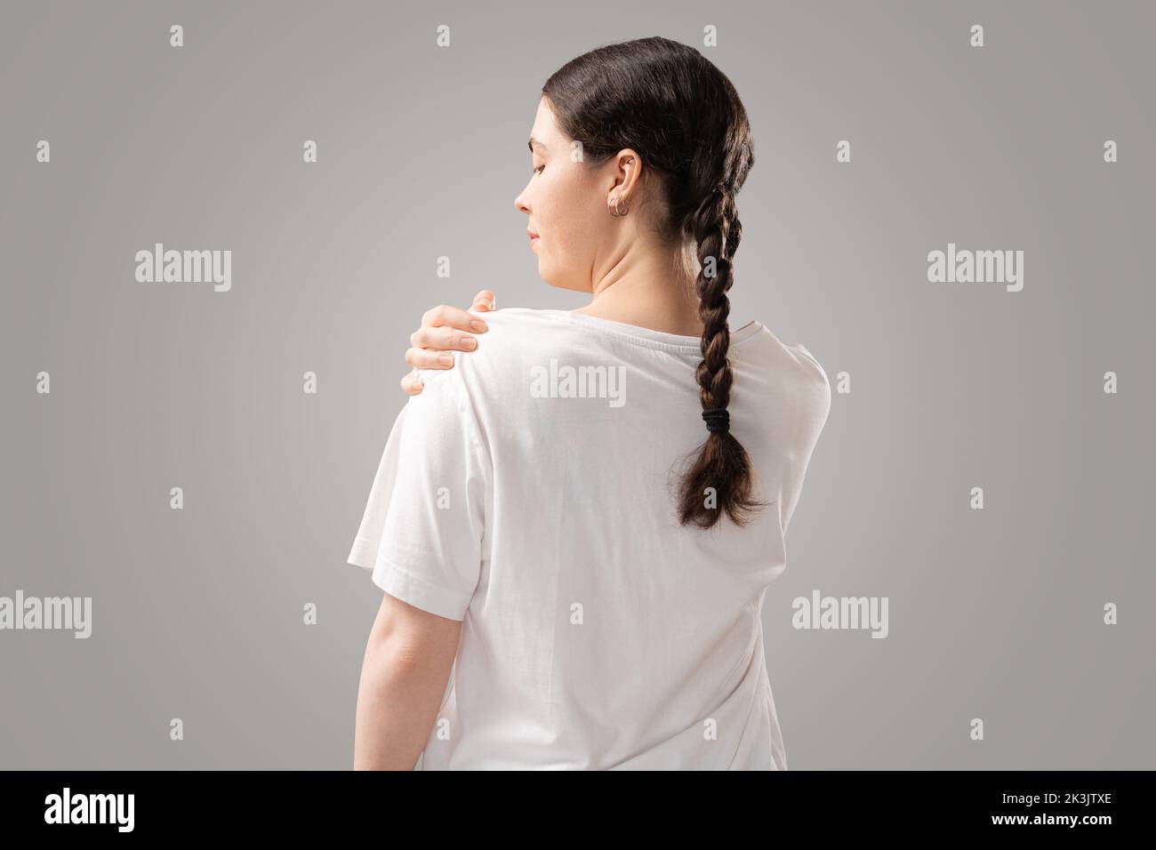 Arthritis and chondrosis. A young woman holds her shoulder with her ...