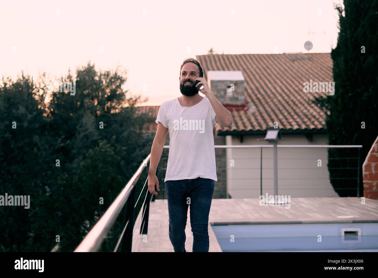 A young handsome man excited having a fun phone call while walking in ...