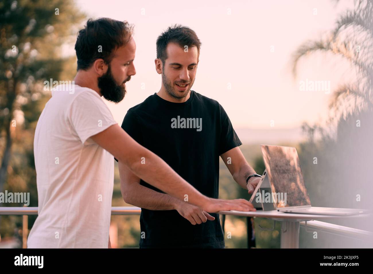 Two young entrepreneur men having a business talk while working online ...