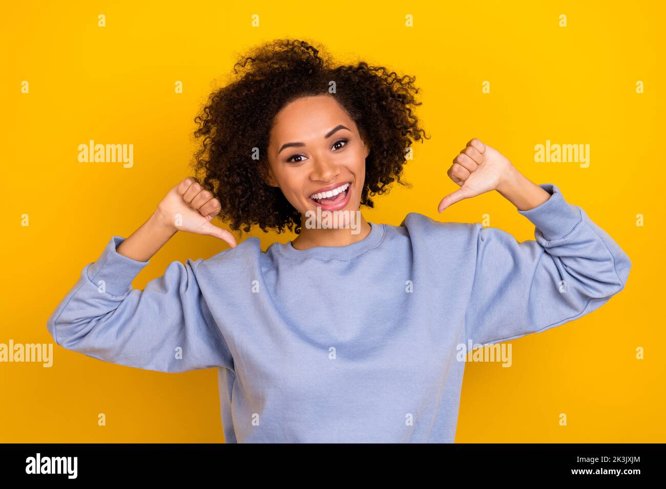 Photo of cheerful impressed curly girl dressed blue pullover pointing ...