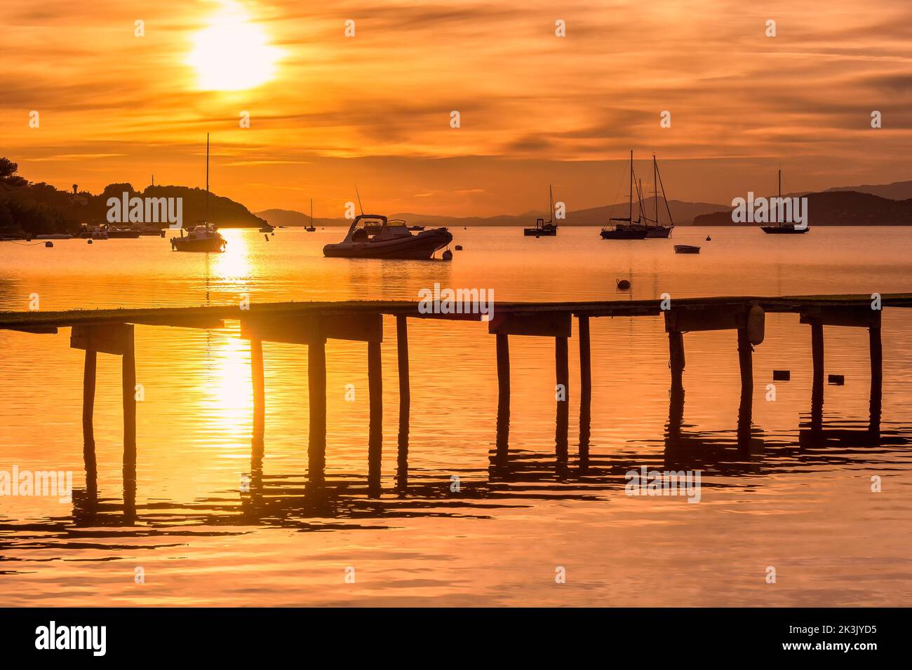 Scenic view of golden sunset over bay with dock and boats on the french ...