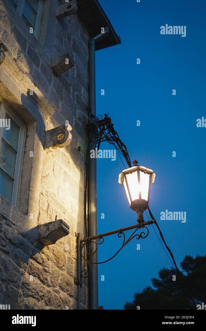 A vertical shot of illuminated light lantern on an old building outside ...
