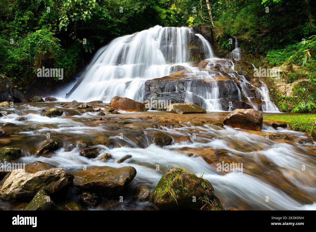 Long-exposure photography technique of smooth flowing water from rocky waterfall inside tropical ...