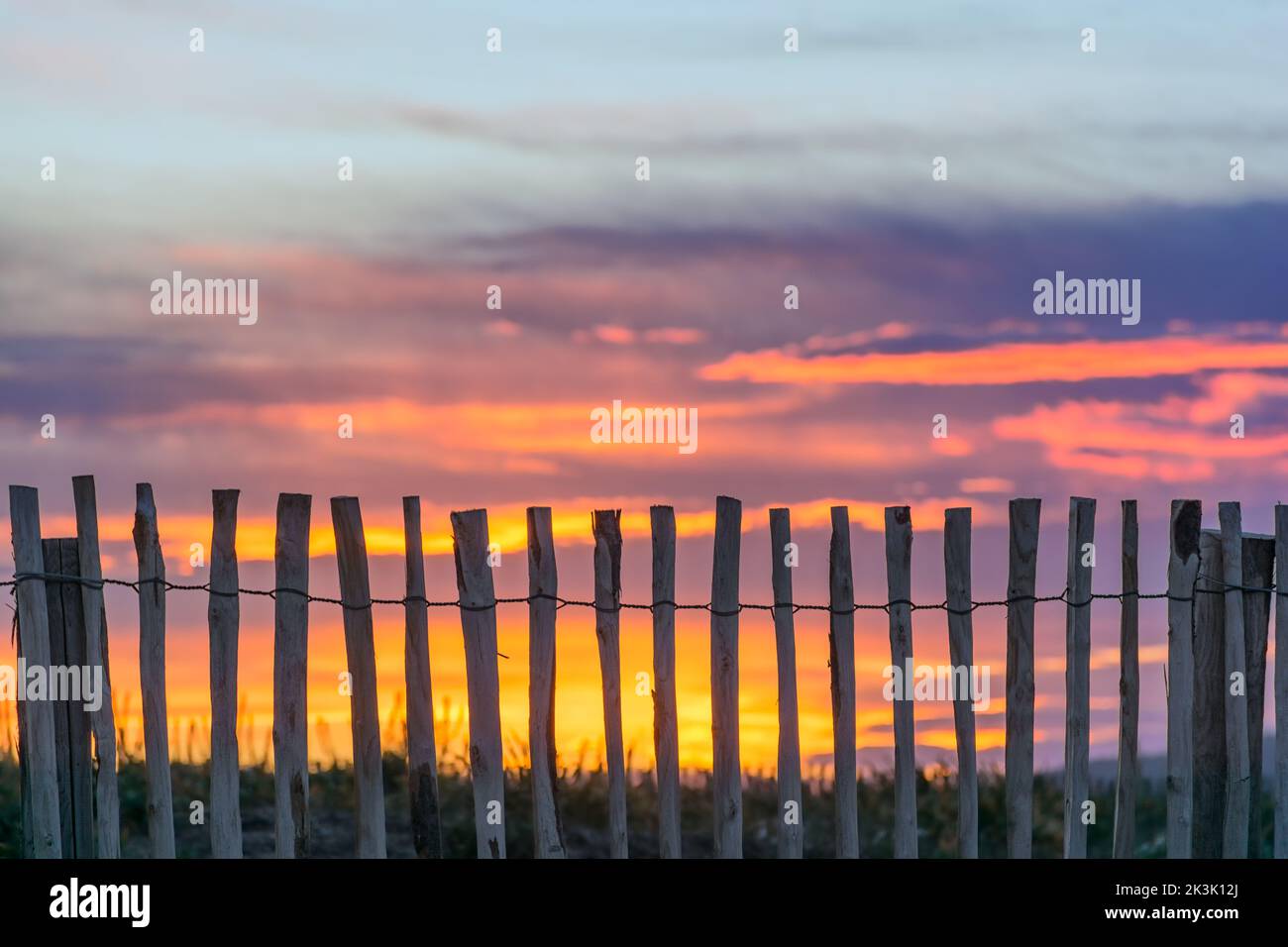 Scenic view of wooden fence at beach against dramatic sunset sky at ...