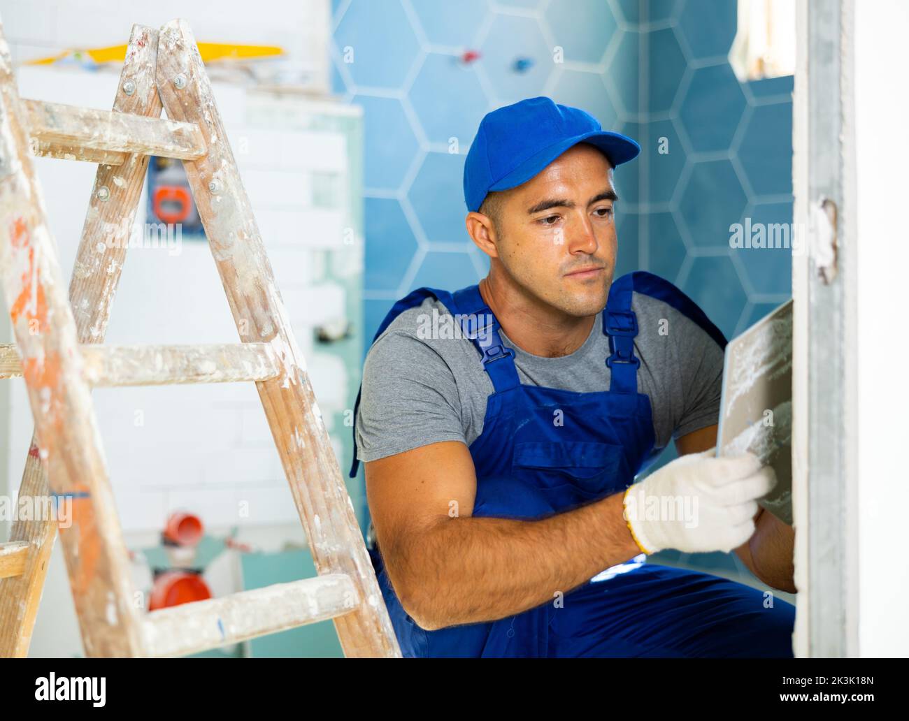 Worker laying tile in bathroom Stock Photo - Alamy