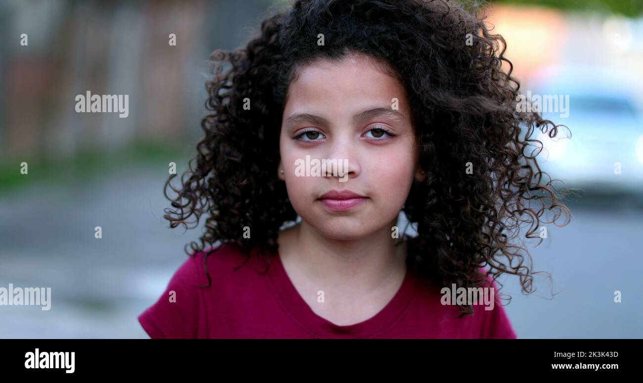 Hispanic little girl looking at camera. Diverse preteen kid standing outside Stock Photo - Alamy