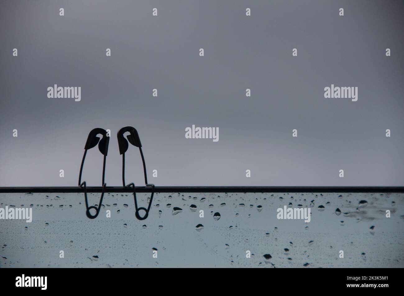Safety pin couple sitting on glass wall with customizable space for ...