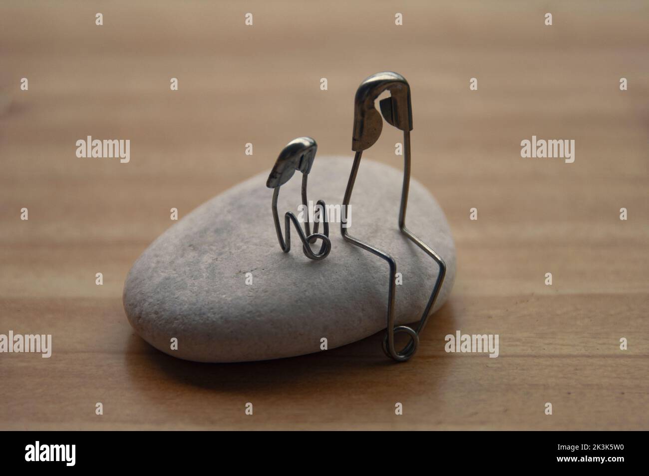 Model safety pin of parent and child sitting on a rock with ...
