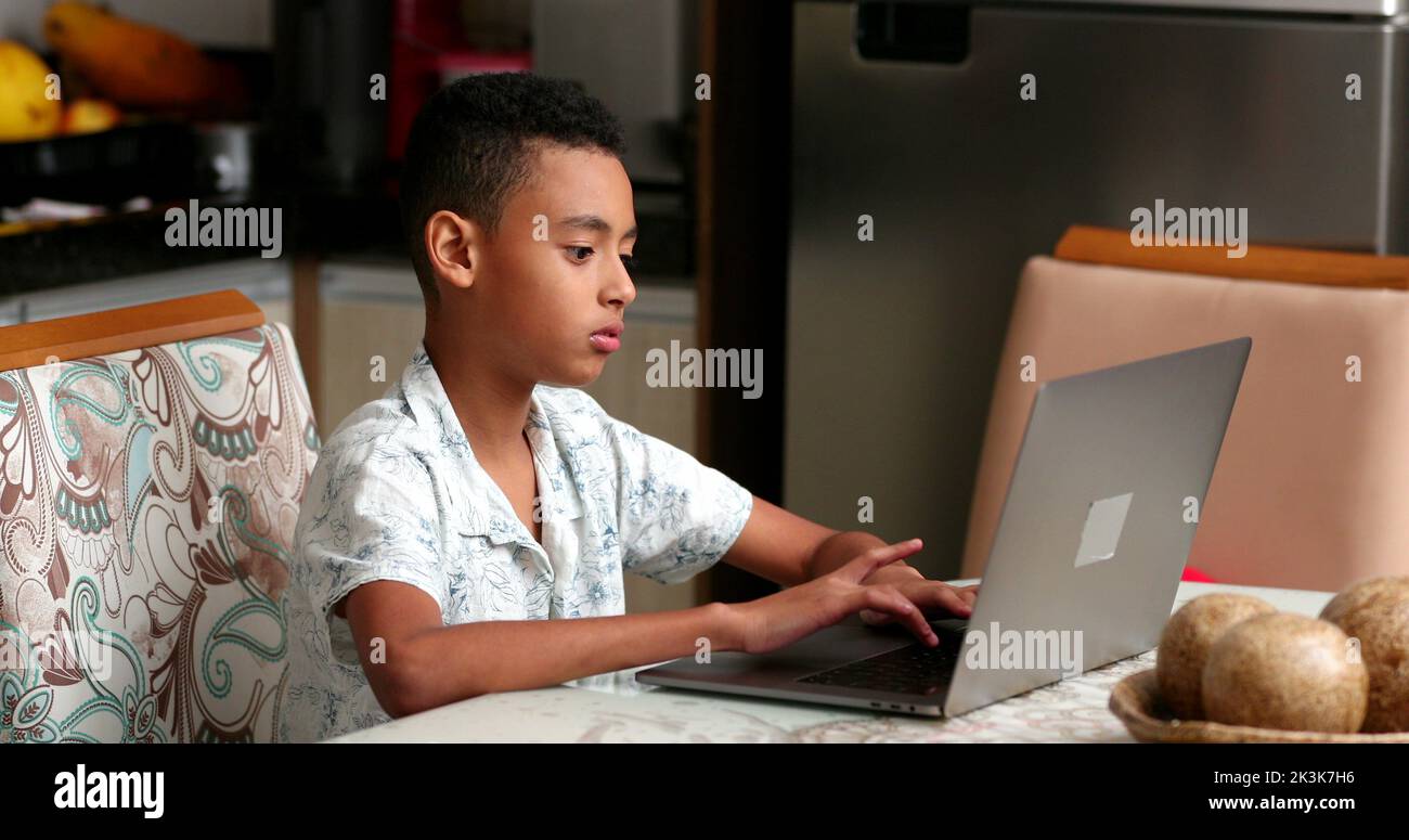 Hispanic boy typing on laptop. South american child using computer for ...