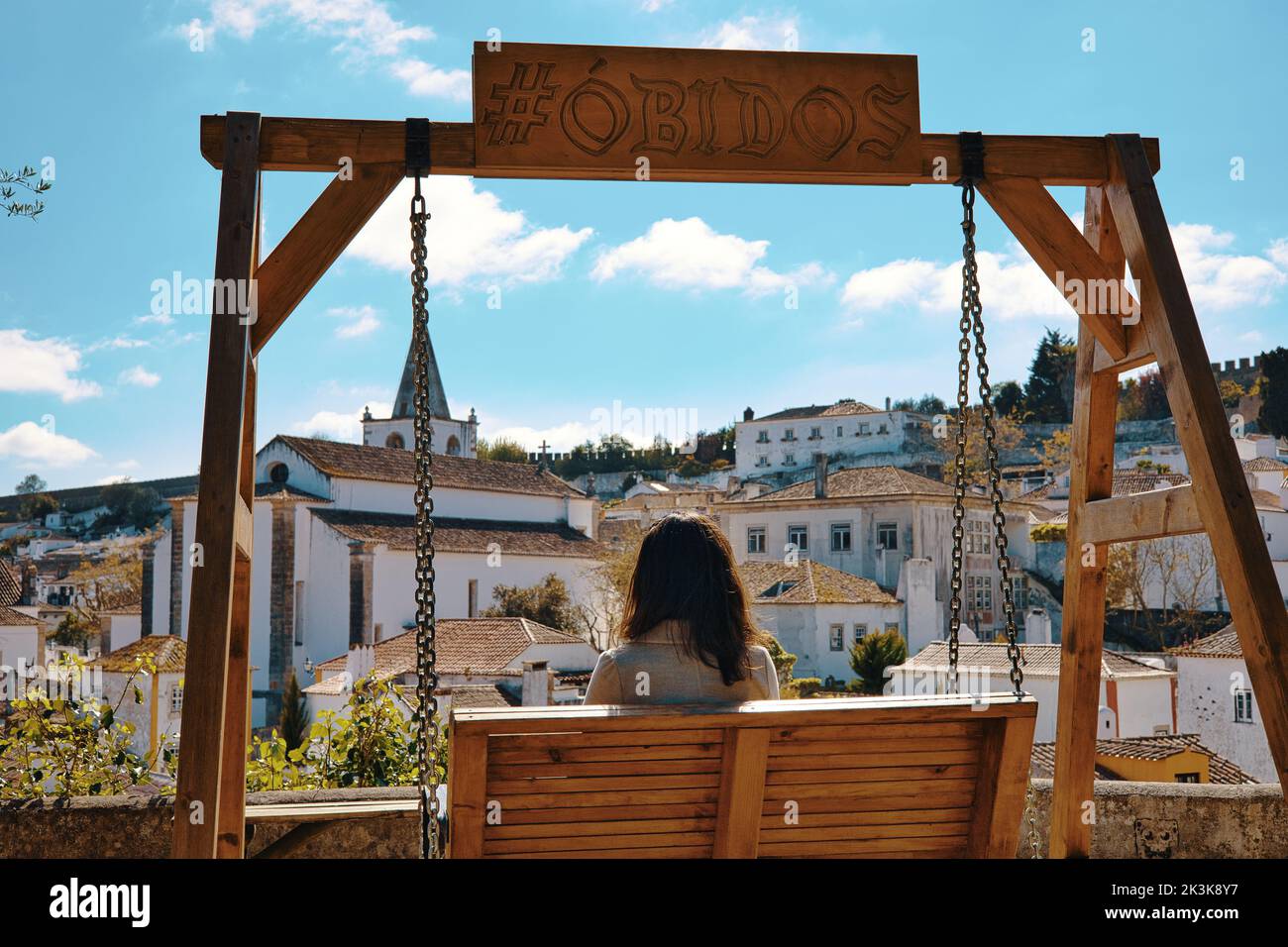 Girl sitting on a swing and watching the medieval city of Óbidos Stock ...