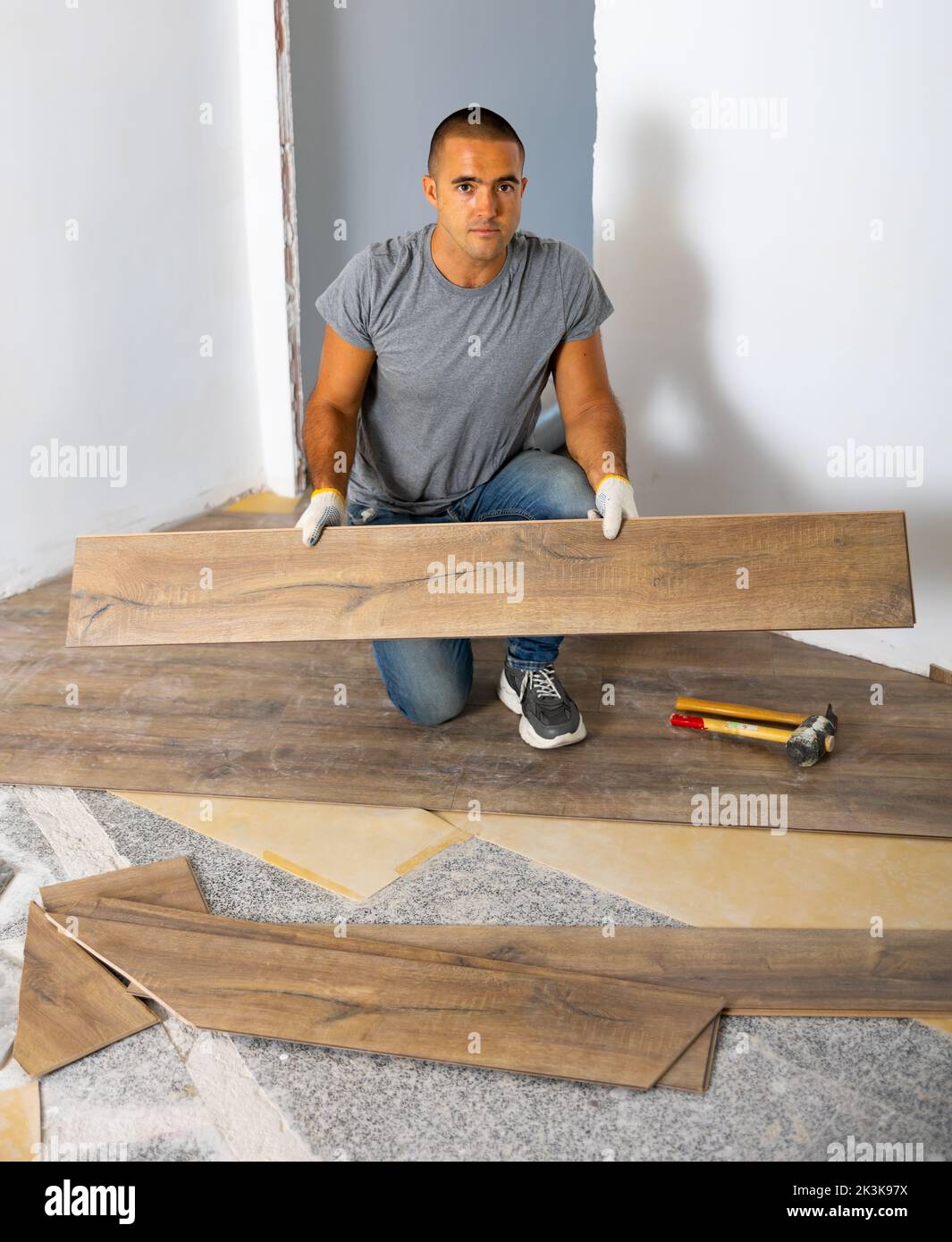 Male worker installing new wooden laminate flooring. The combination of ...