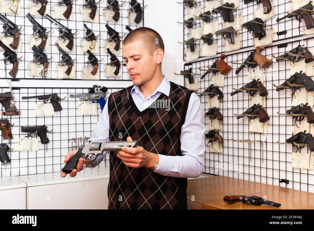 Man chooses revolver in gun store Stock Photo - Alamy