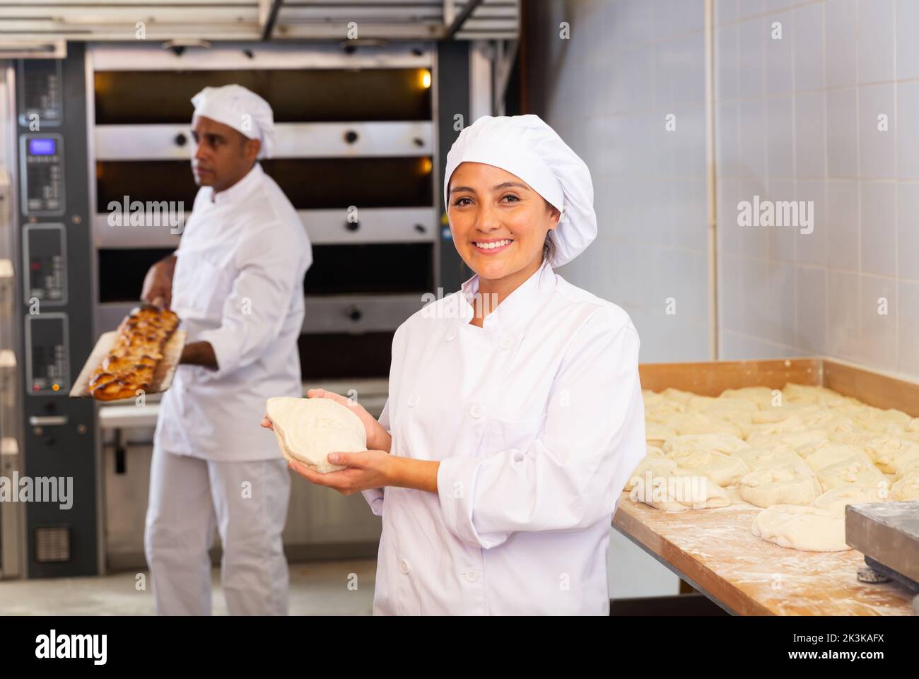 Portrait of woman baker with dough in hand in bakery kitchen Stock ...