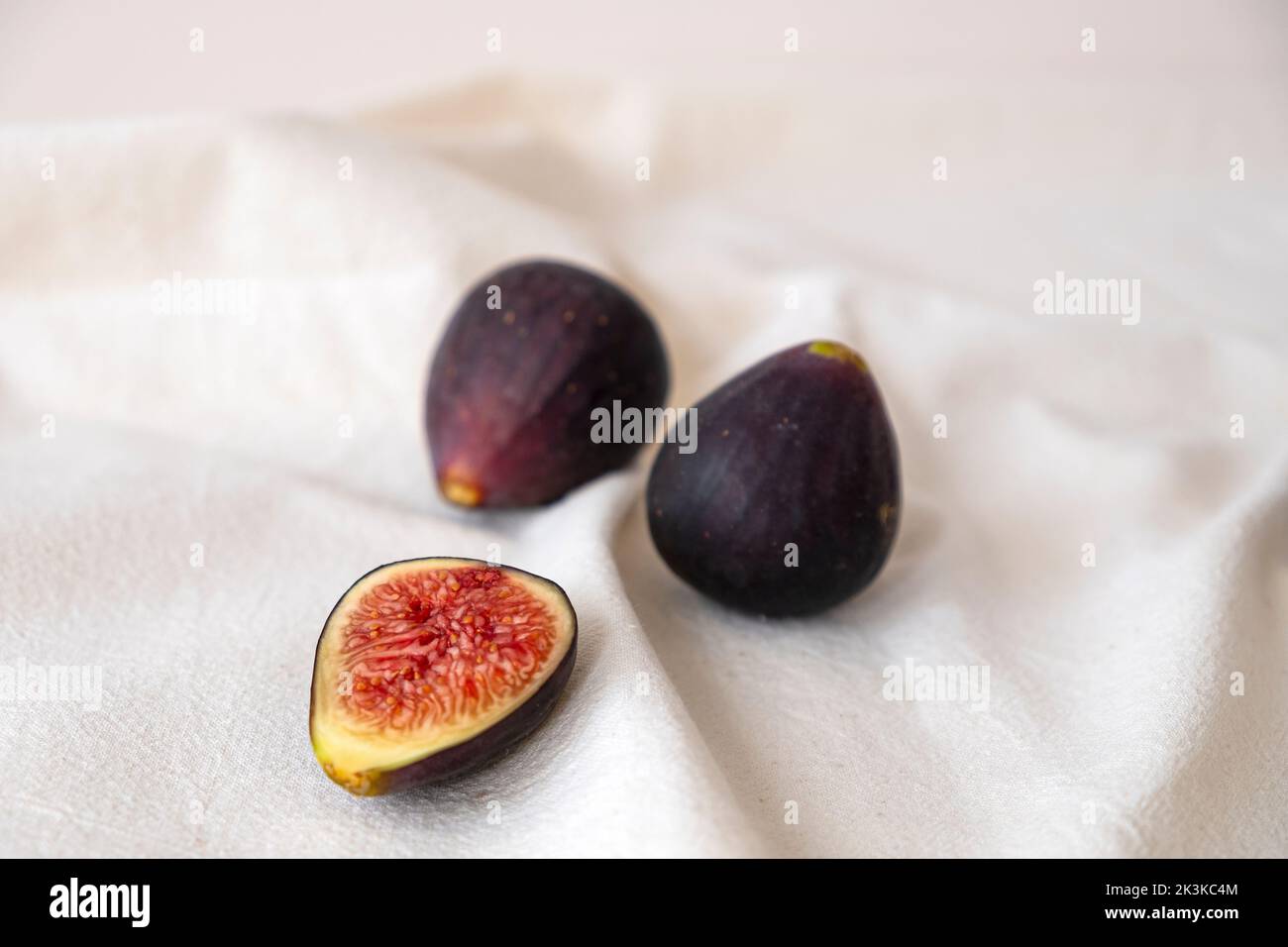 Fresh ripe and sweet figs cut and whole on beige color table cloth ...