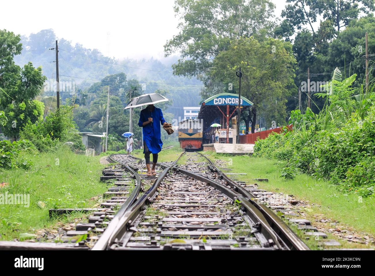 Man walking on the railway on a rainy day. He has an umbrella in his ...