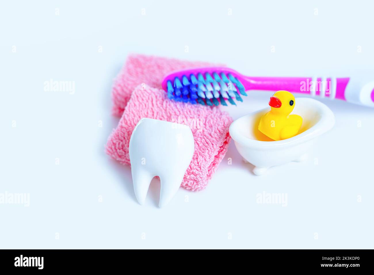 White tooth placed on pink terry towels with a yellow duck bath toy in ...