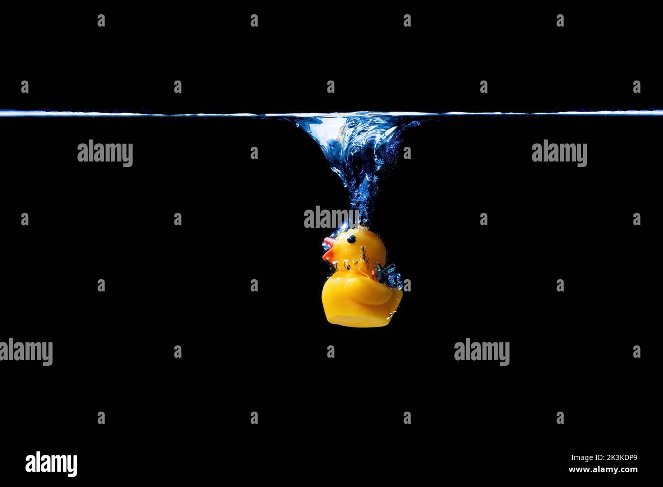 Close-up of a toy yellow duck falling underwater isolated on black ...