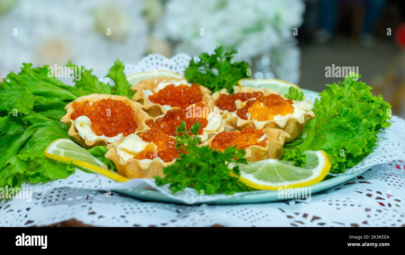 Red caviar and grated cheese in small dough baskets. A delicious cold ...