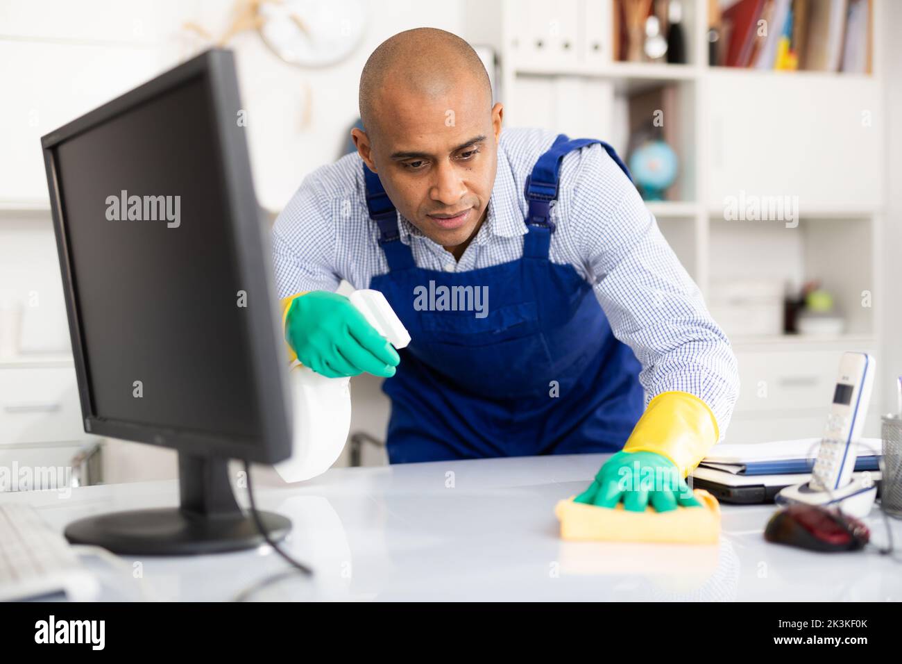 Latin american male cleaner washing computer desk in office Stock Photo ...