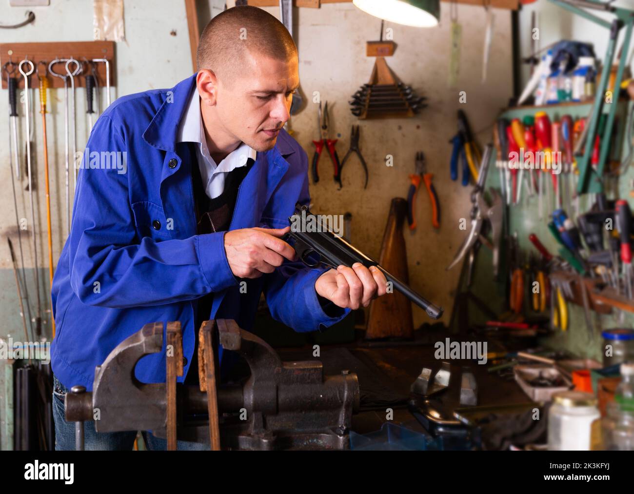 Gunsmith disassembles and repairs pistol in weapons workshop Stock ...