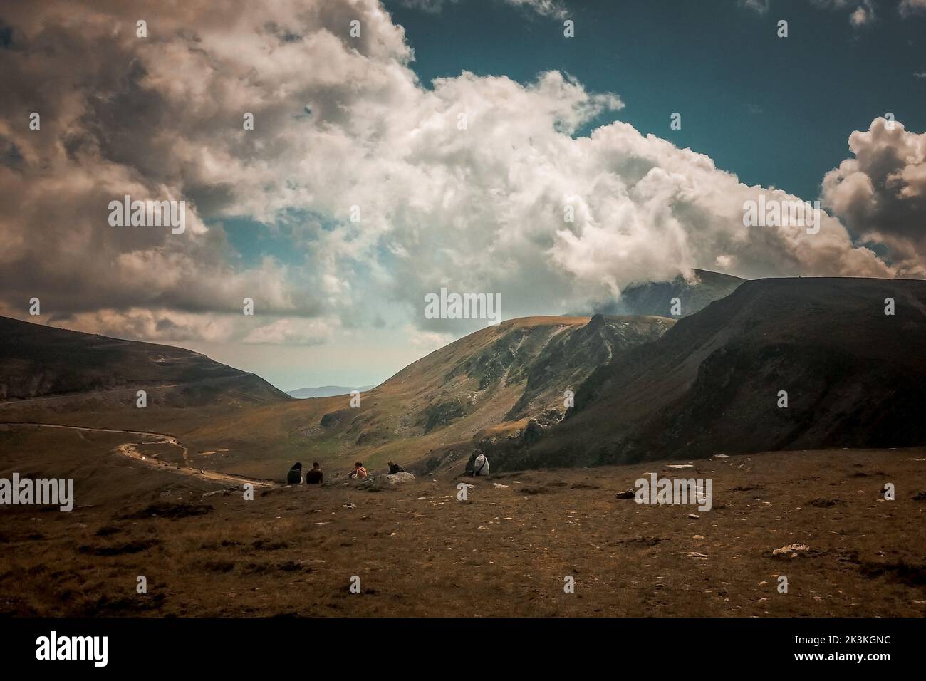 A beautiful shot of tourists at the top of a mountain under the cloudy ...