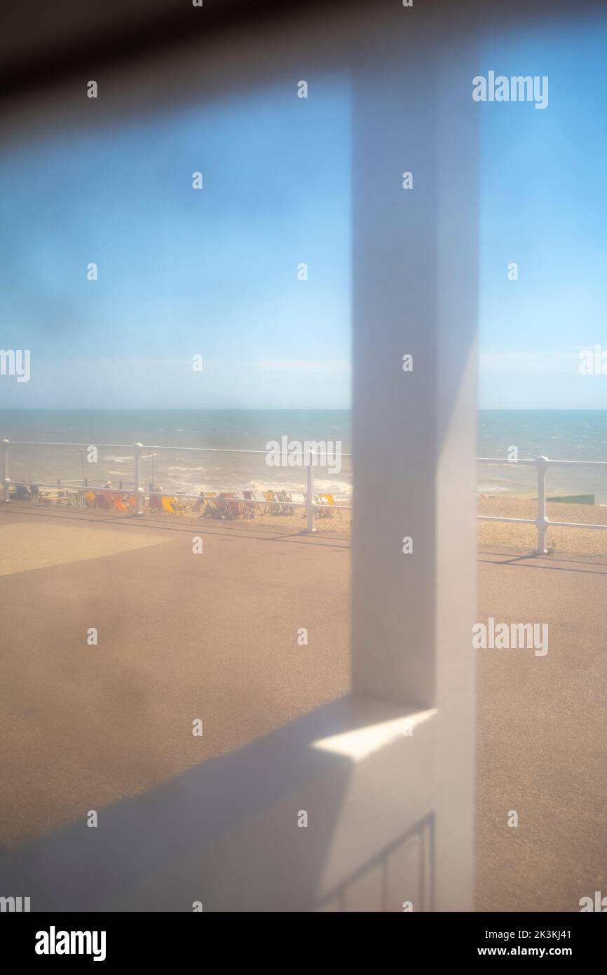 View of deckchairs on Hastings beach from a bus stop on the promenade ...