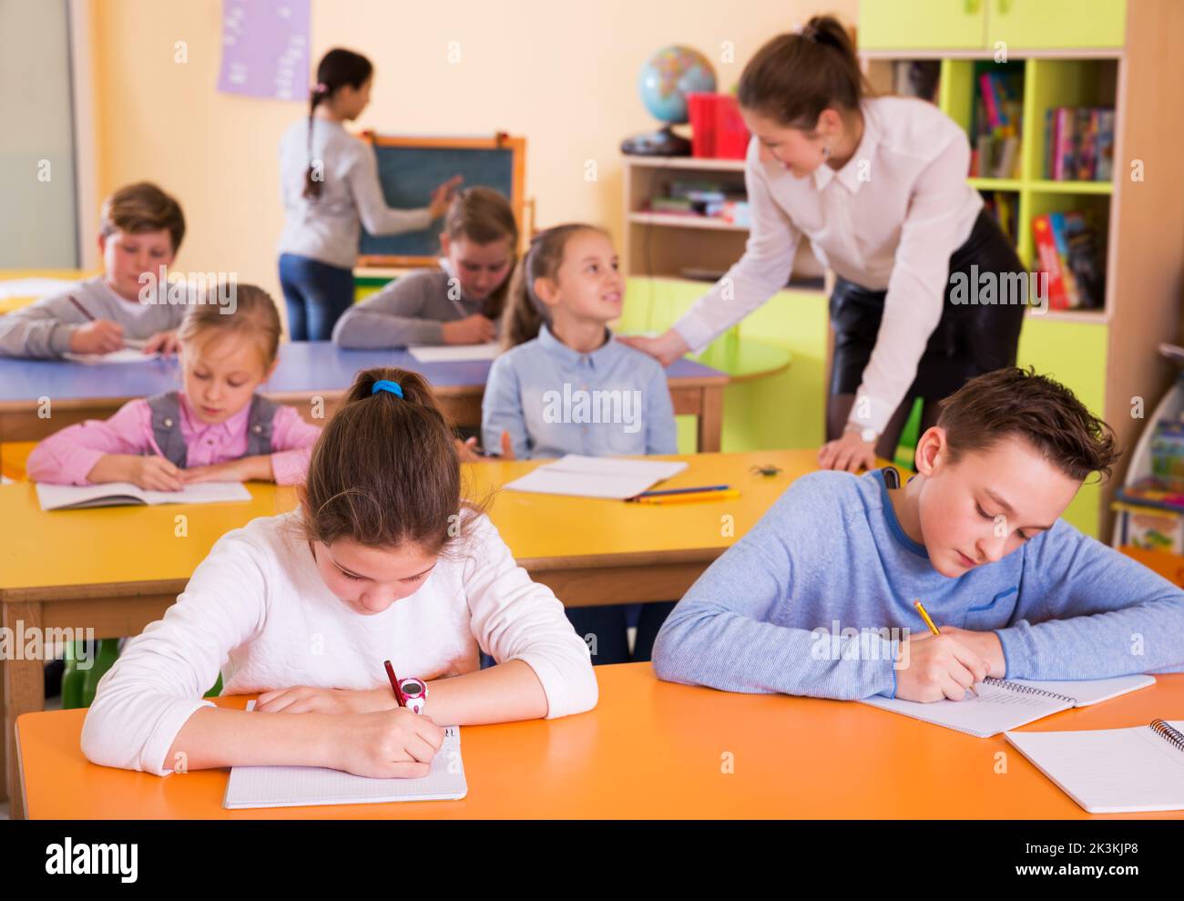Kids studying and teacher helping Stock Photo - Alamy