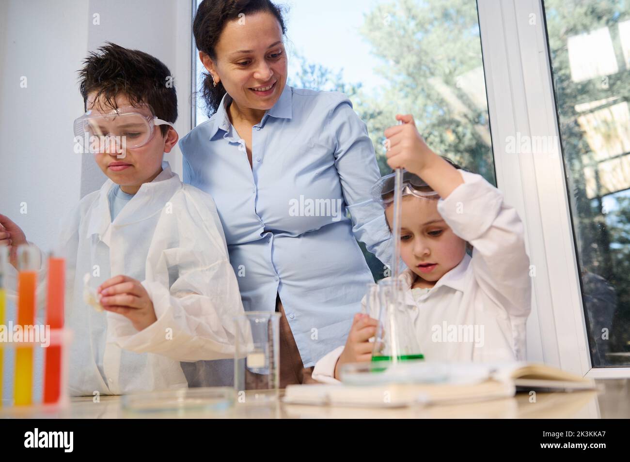 Happy school kids with scientist doing science experiments in the ...