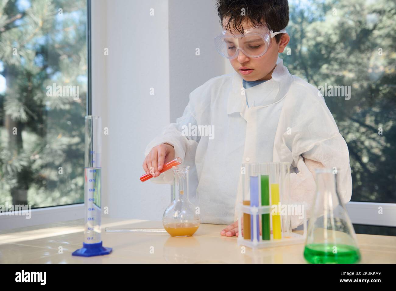 Elementary student boy conducting a chemical experiment, holding test ...