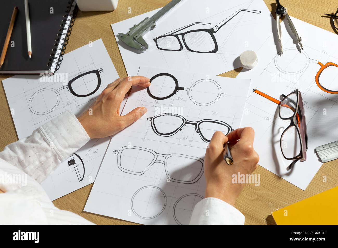 The designer draws a sketch of eyeglasses on paper. Creating glasses ...